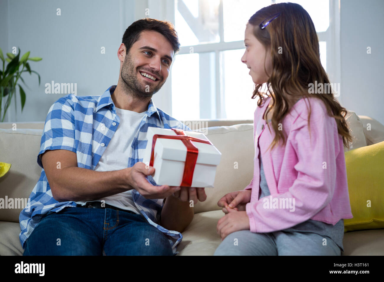 Father giving gift to daughter in the living room Stock Photo - Alamy