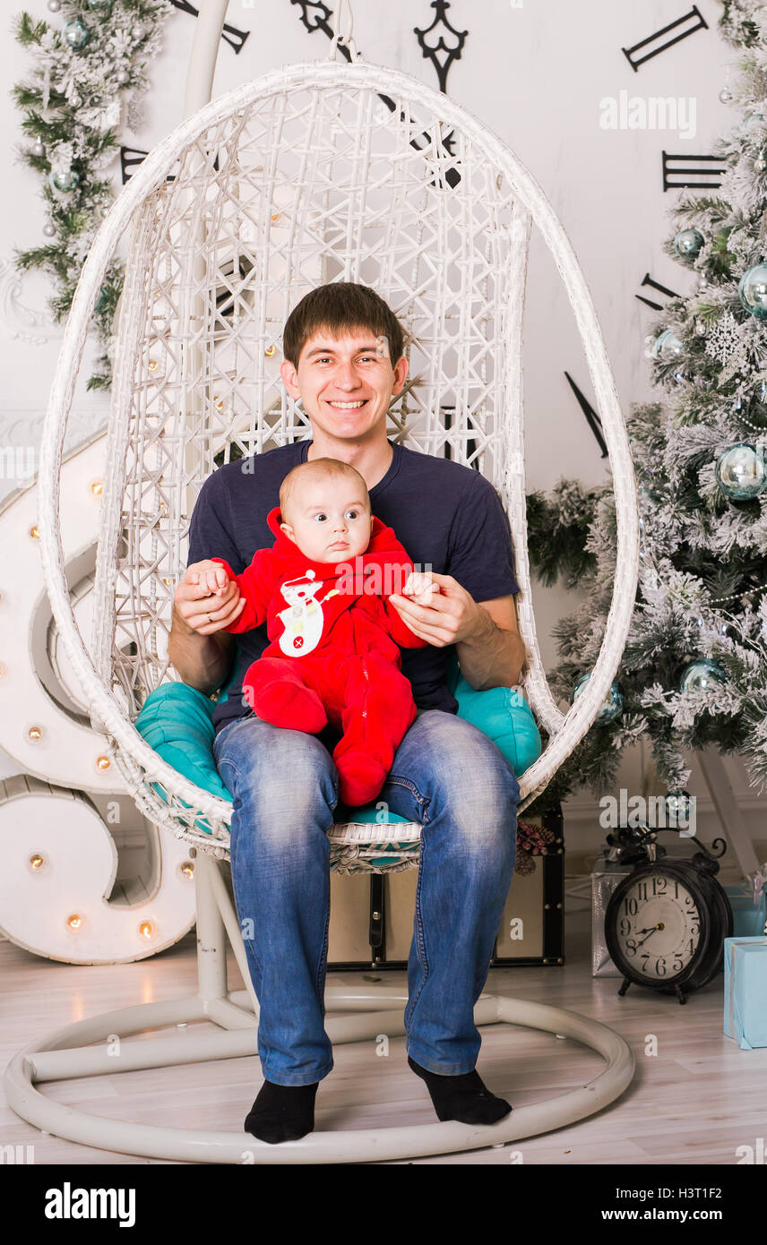 Portrait of happy young father sitting in chair and playing with his ...