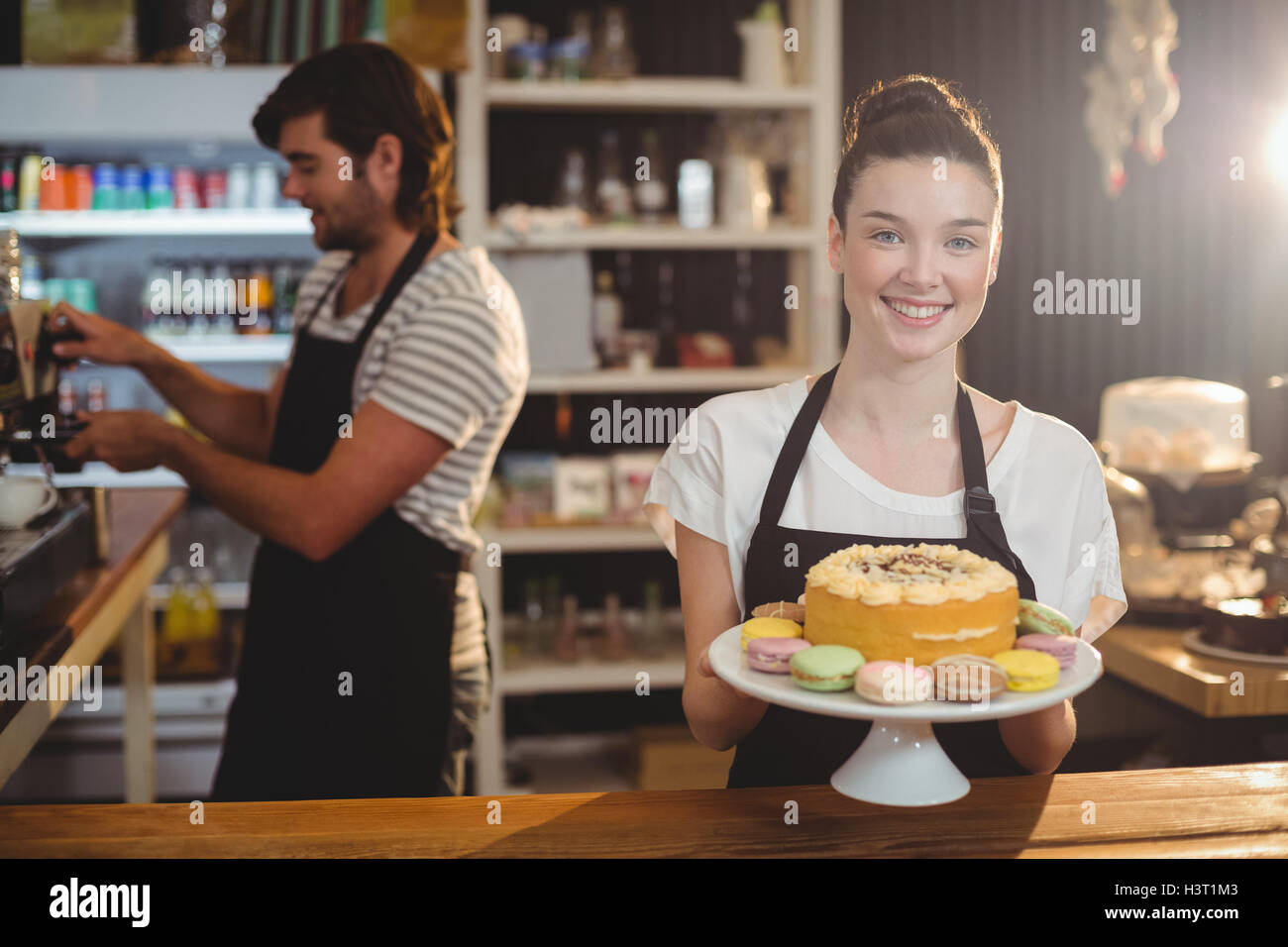 Portrait of waitress holding dessert on cake stand Stock Photo - Alamy