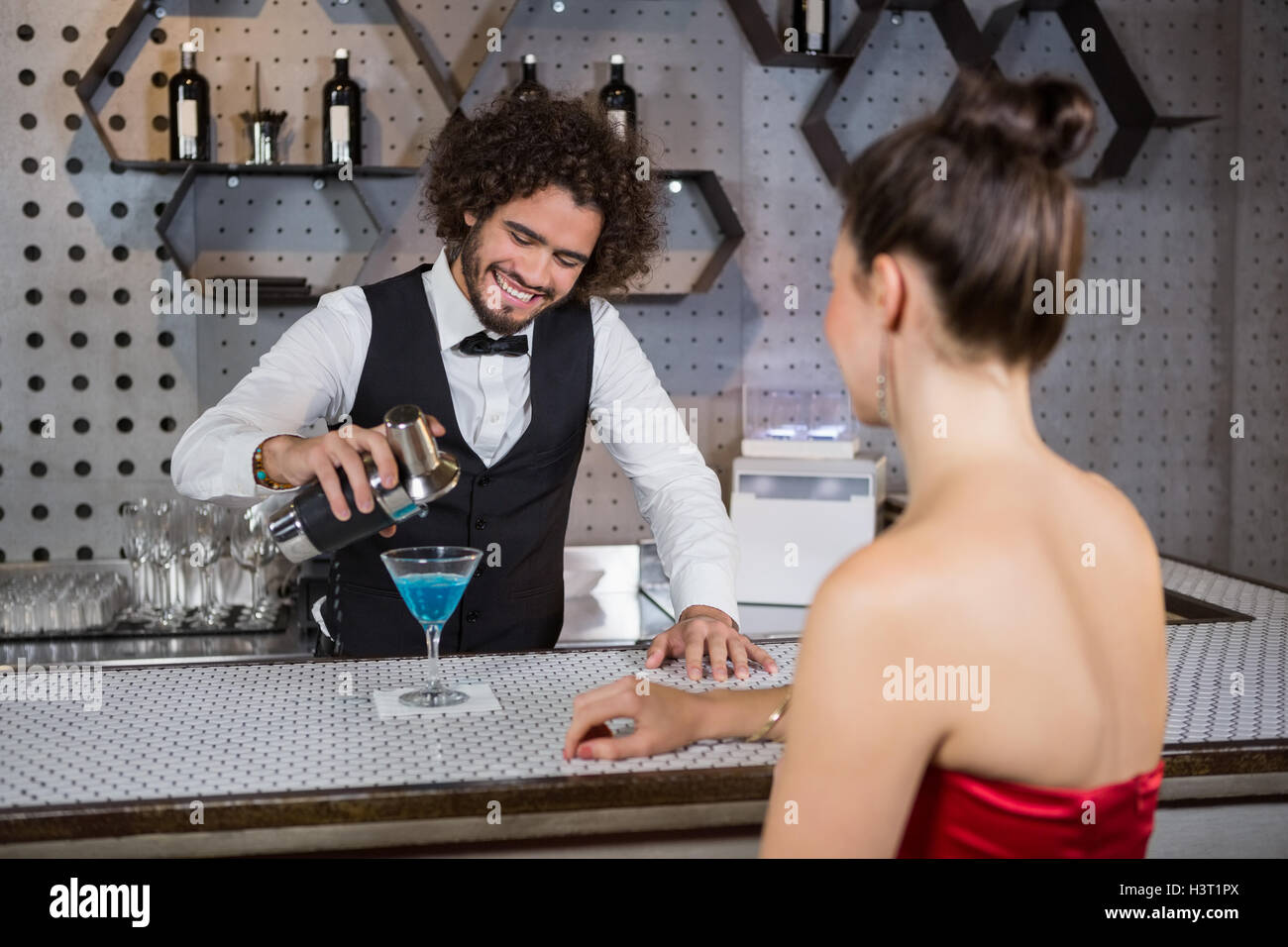 Waiter pouring cocktail in womans glass at bar counter Stock Photo - Alamy