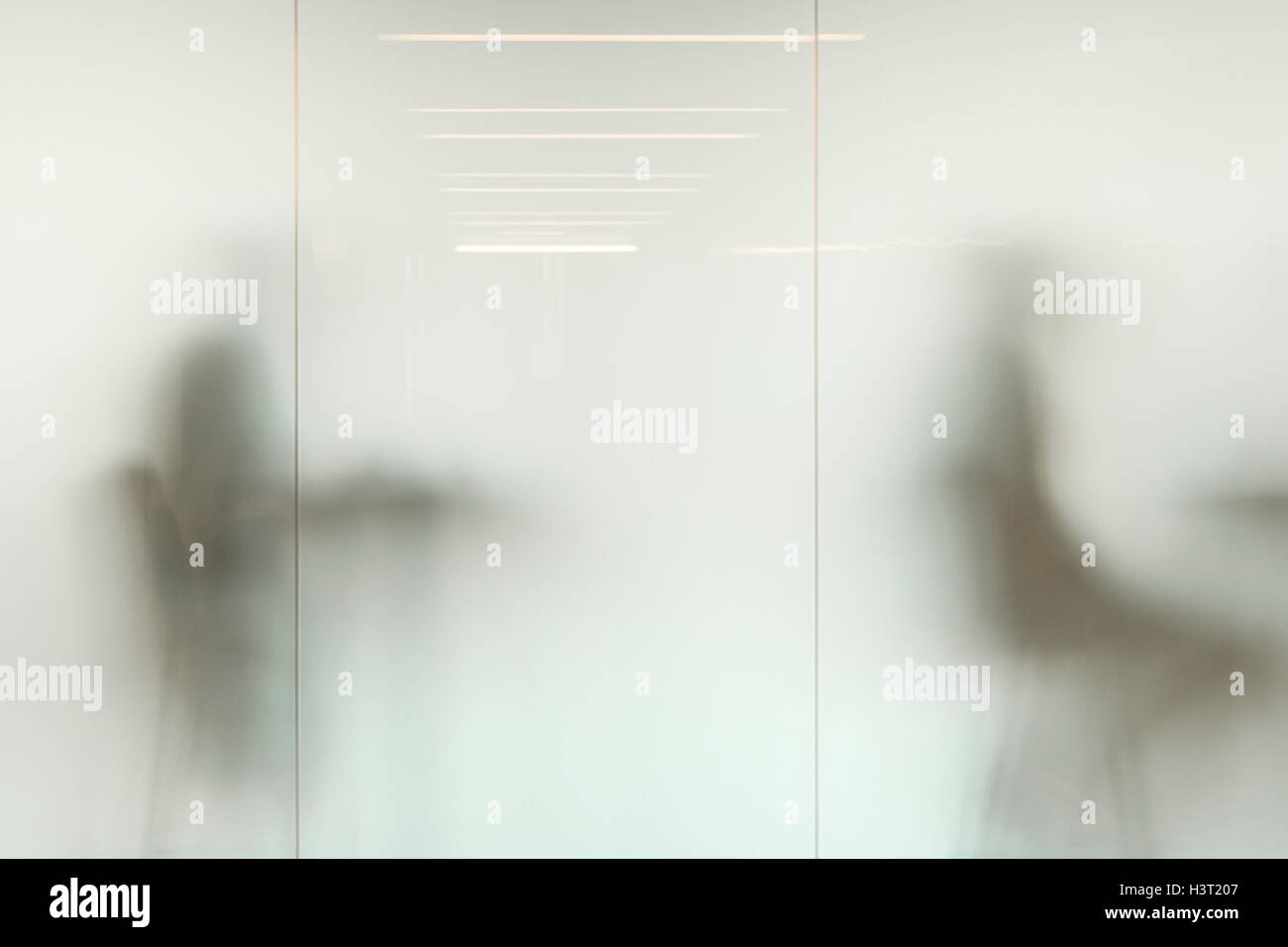 Blurred seated figures behind a frosted glass partition Stock Photo - Alamy