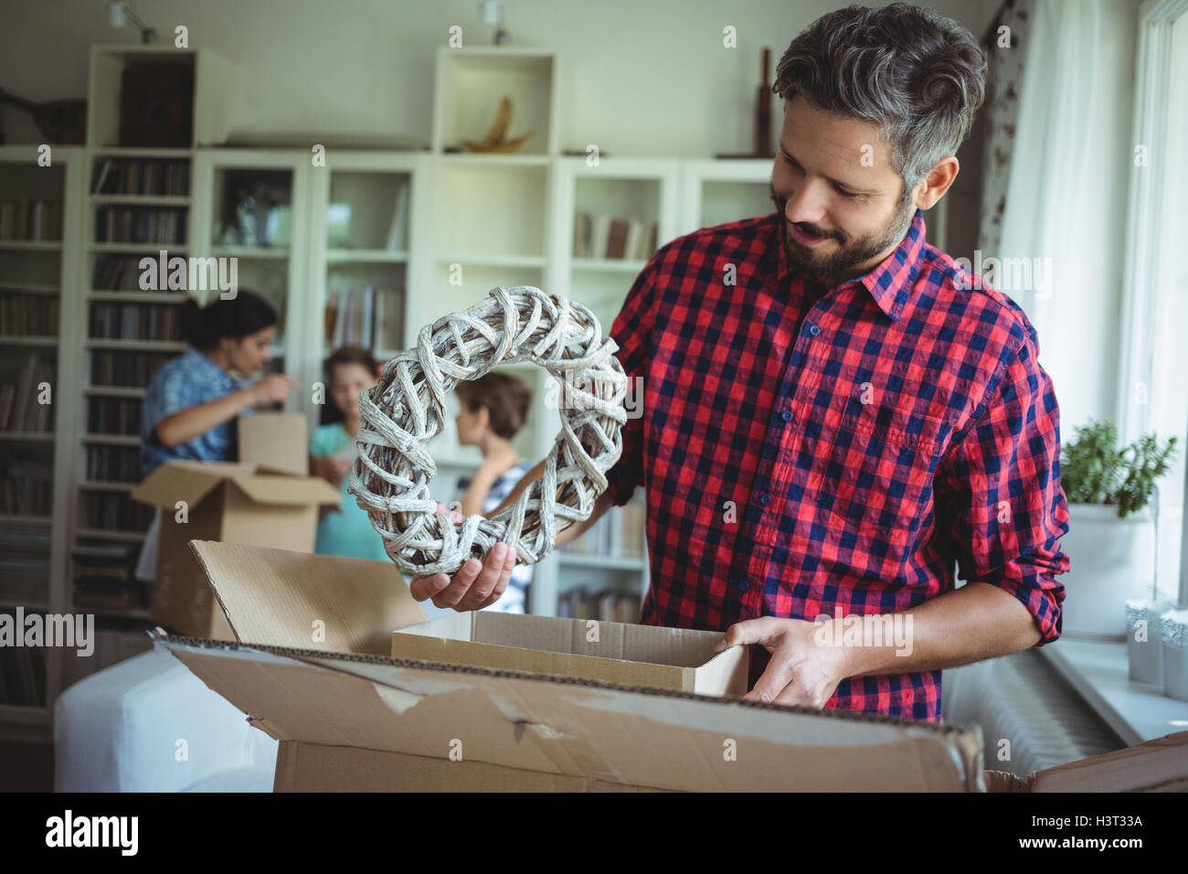 Man unpacking cartons while family standing in background Stock Photo ...