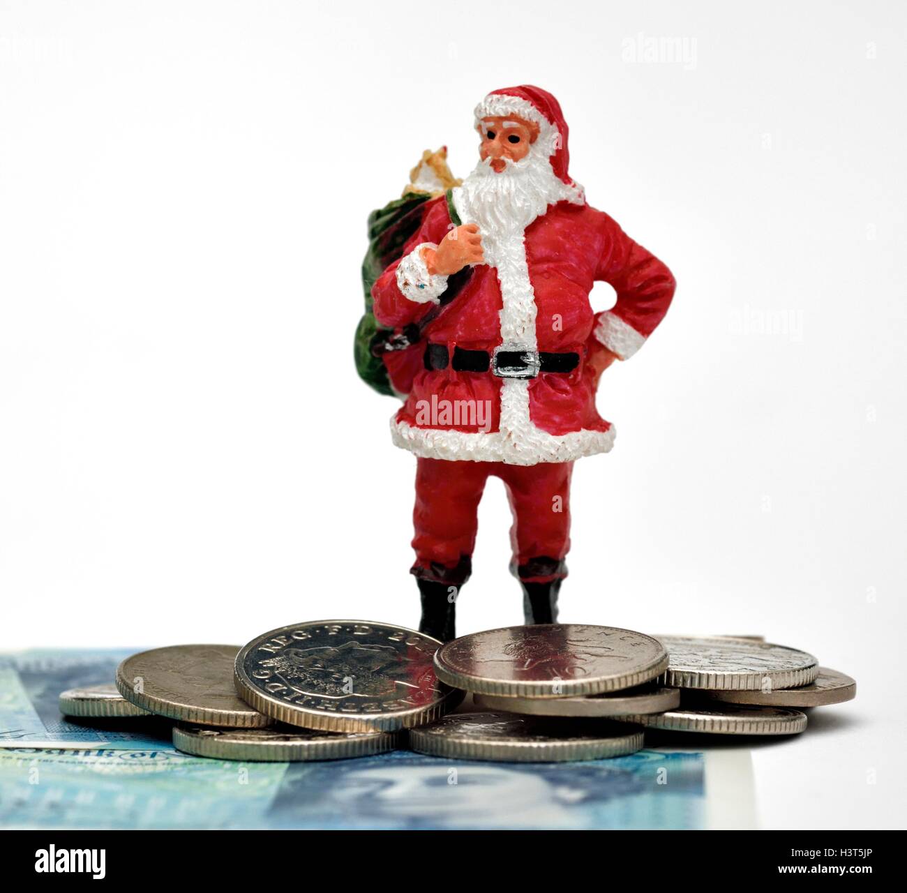A santa claus figurine standing on some new five pound notes and coins ...