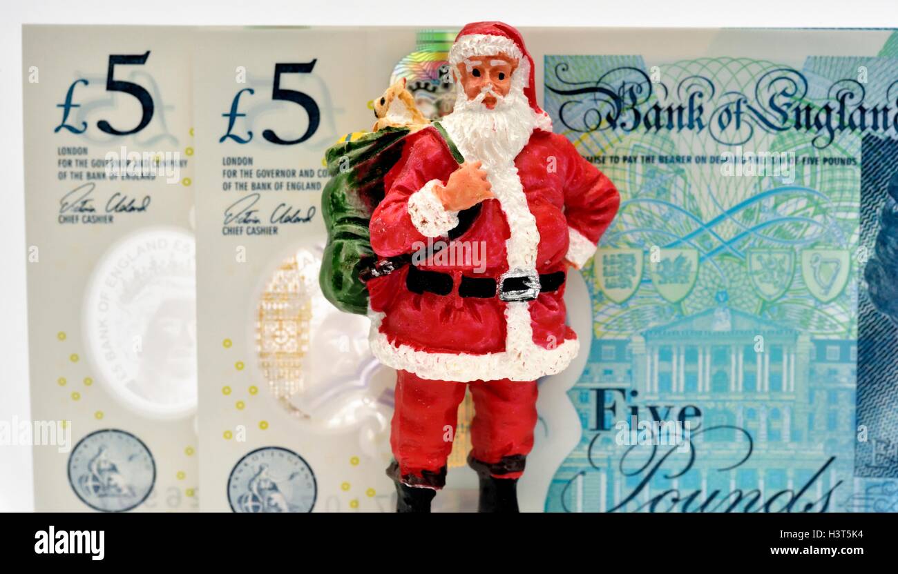 A santa claus figurine standing in front of some new five pound notes ...