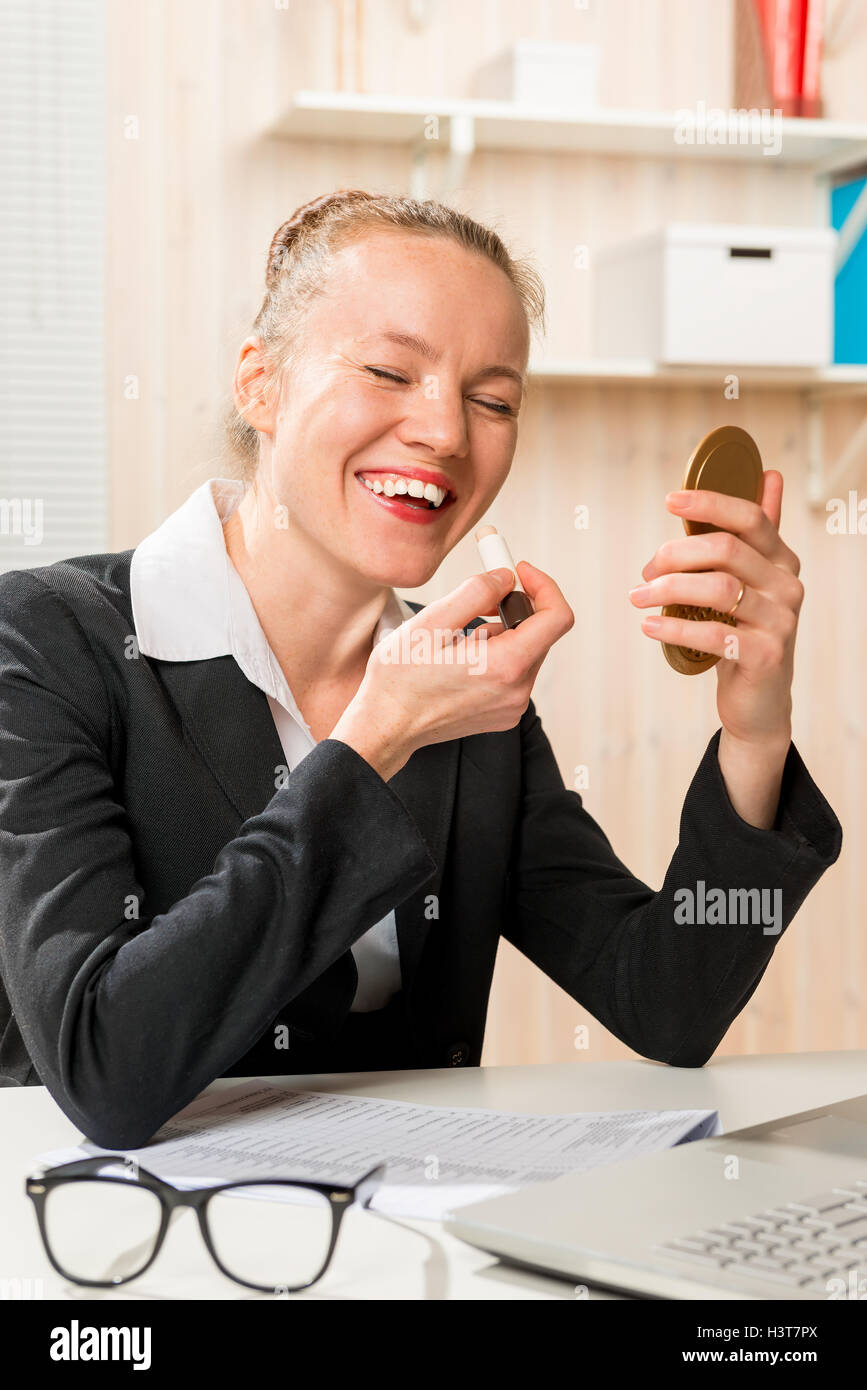 laughing secretary corrects make-up in the workplace in the office ...