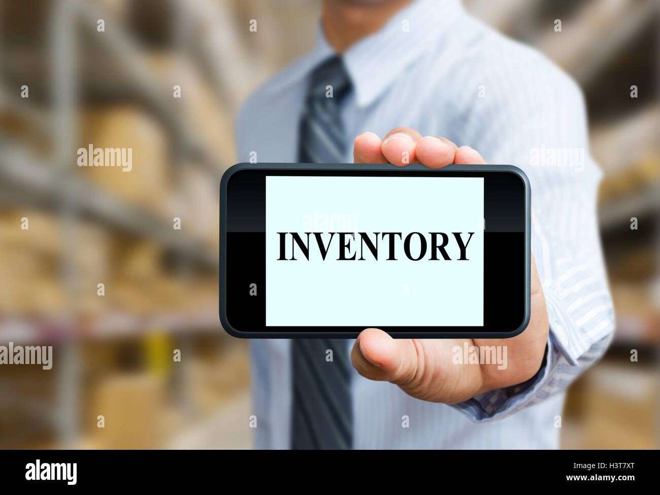 businessman holds mobile phone showing inventory wording Stock Photo ...