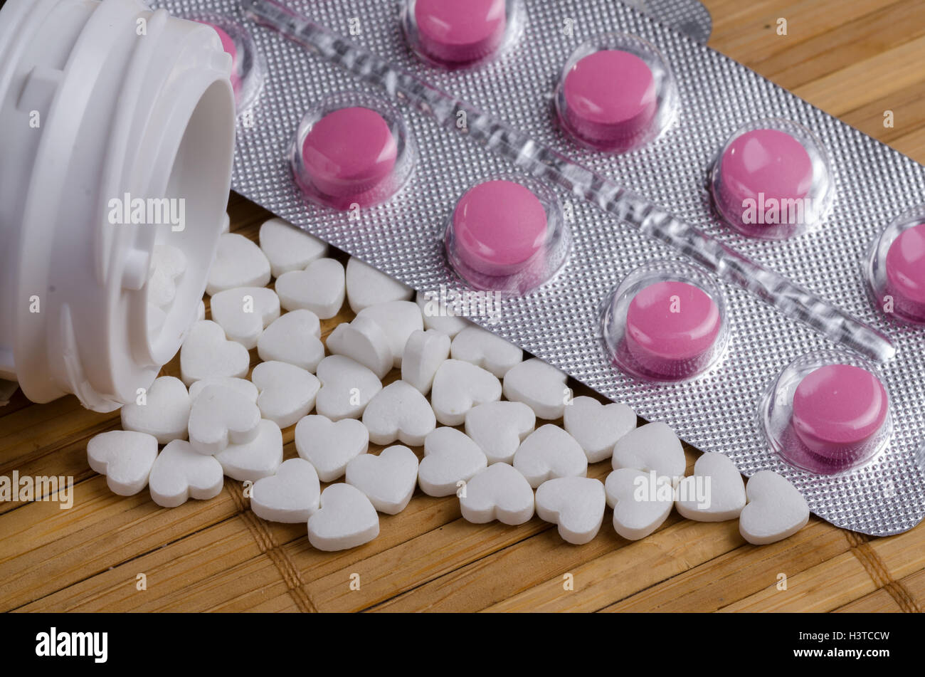 Pink and white pills in the form of heart close up Stock Photo - Alamy
