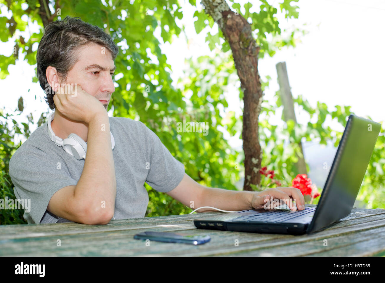 man sitting outdoor working with a laptop Stock Photo - Alamy