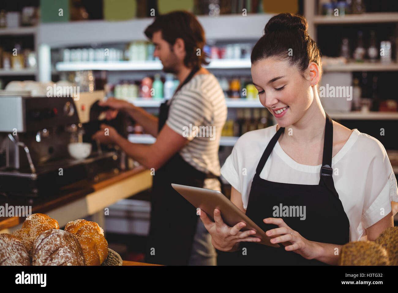 Smiling waitress standing at counter using digital tablet Stock Photo ...