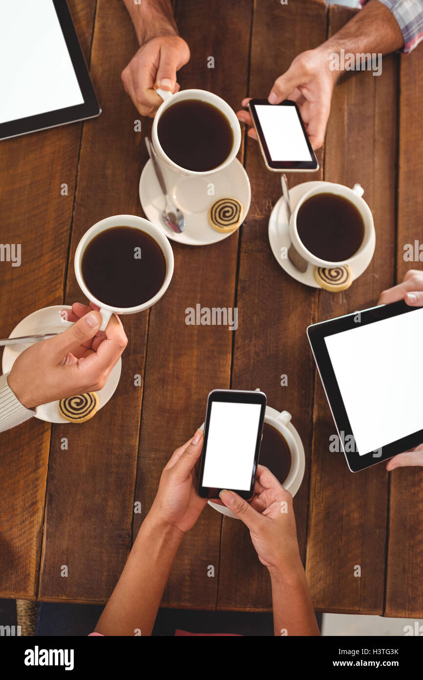 Group of friends using mobile phone while having cup of coffee Stock ...