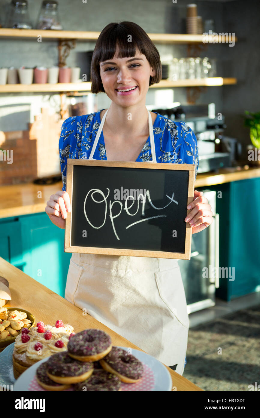 Smiling waitress standing with a open sign Stock Photo - Alamy