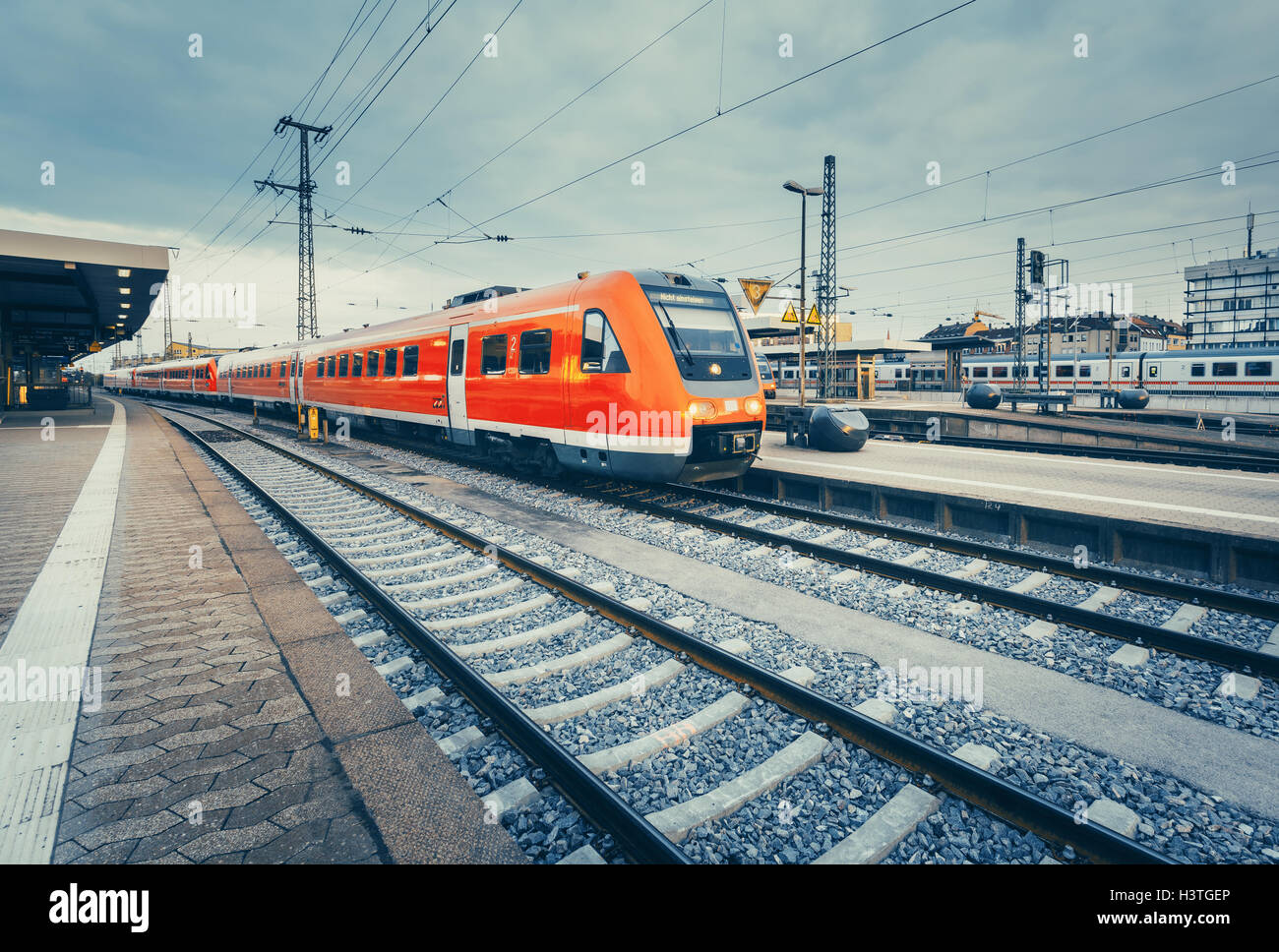 Beautiful railway station with modern high speed red commuter train at ...