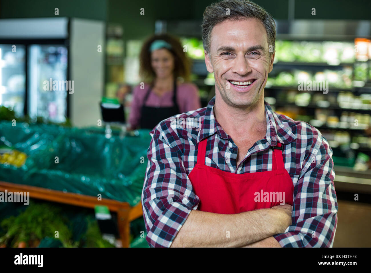 Smiling male staff standing with arms crossed in organic section Stock ...