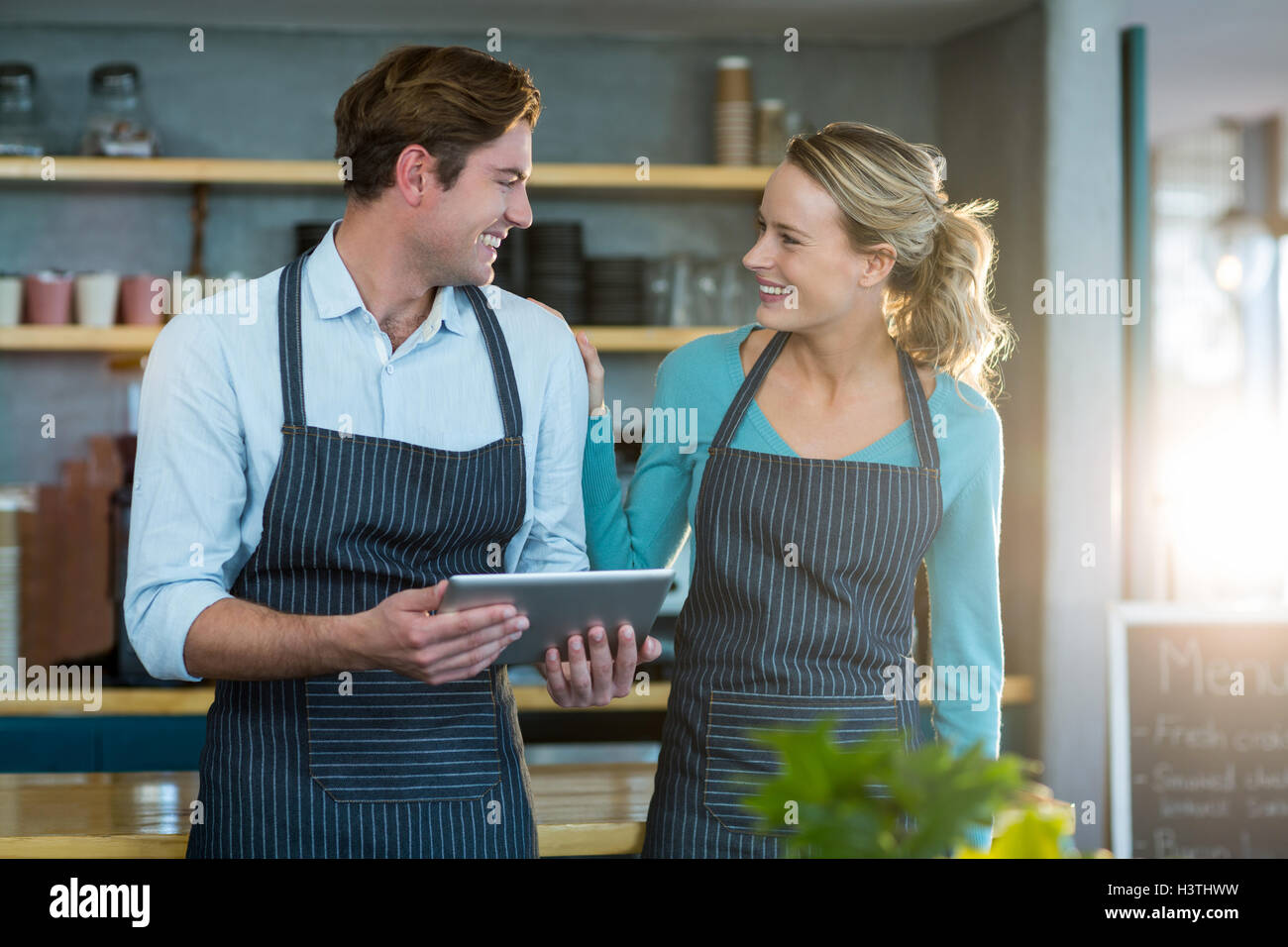 Smiling waiter and waitress interacting while using digital tablet ...