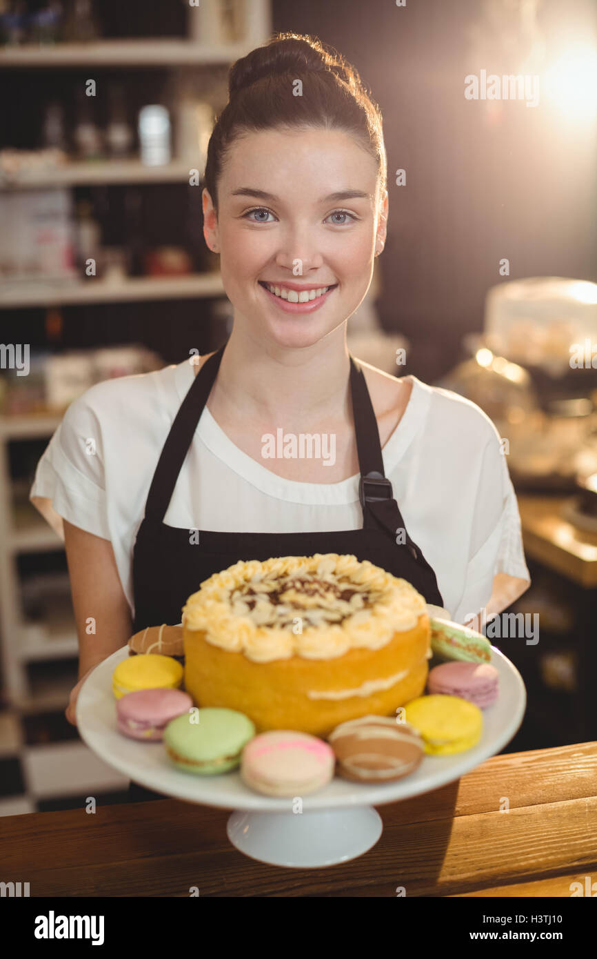 Portrait of waitress holding dessert on cake stand Stock Photo - Alamy