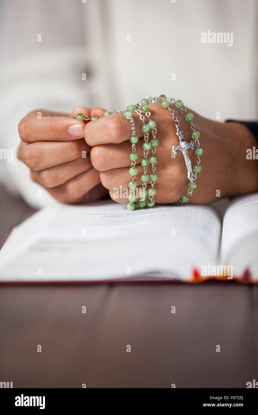 Praying hands of woman with a rosary on bible Stock Photo - Alamy
