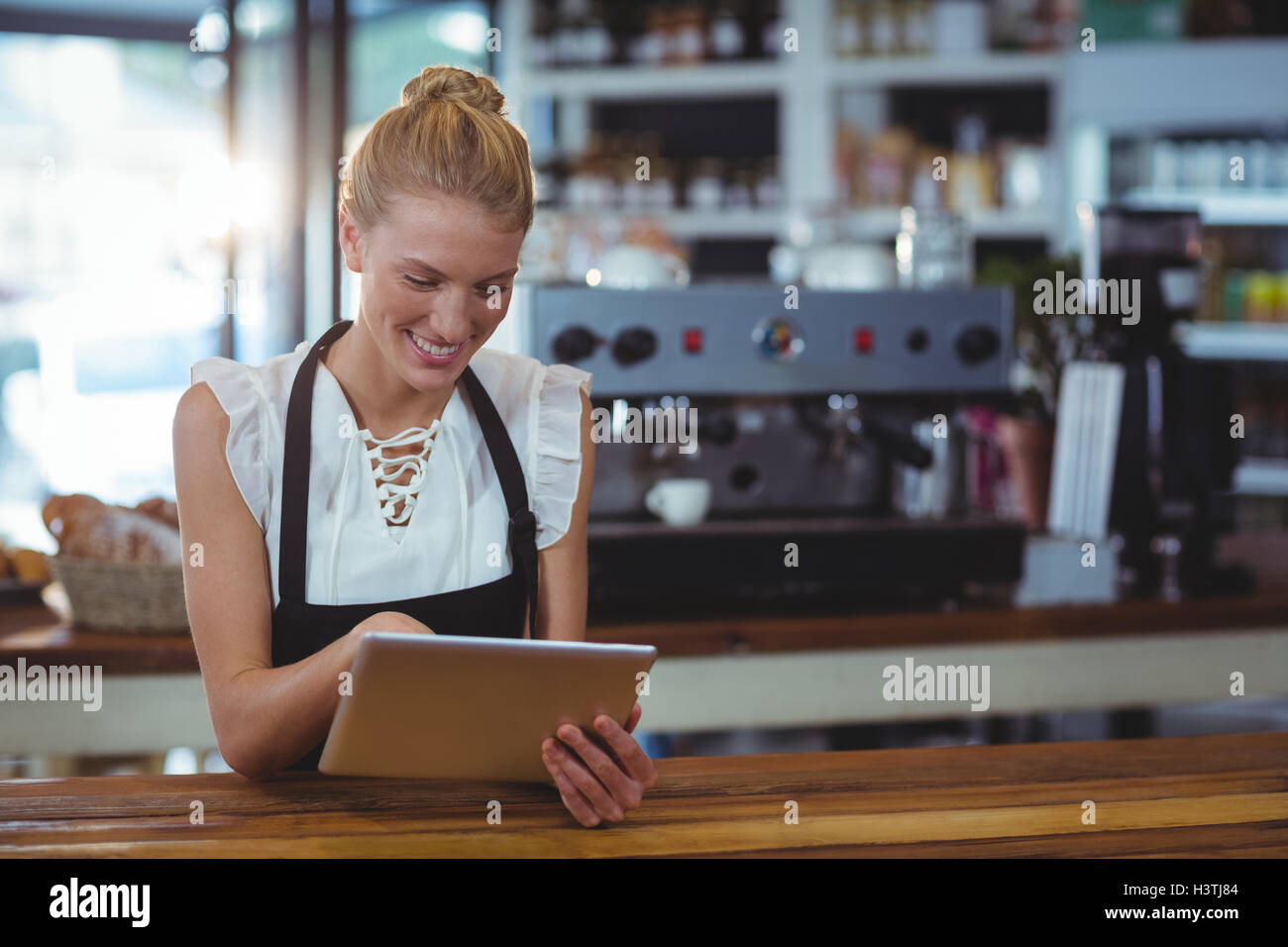 Smiling waitress standing at counter using digital tablet Stock Photo ...