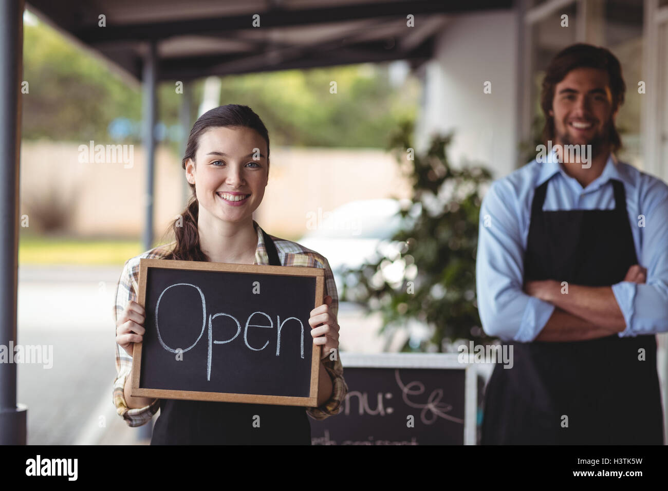 Waiter and waitress standing with chalkboard with open sign Stock Photo ...