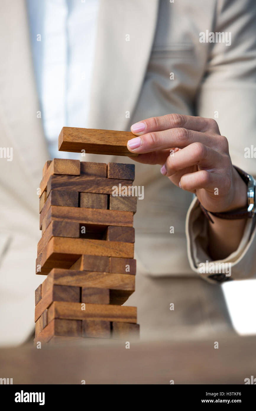 Businesswoman placing wooden block on a tower Stock Photo - Alamy