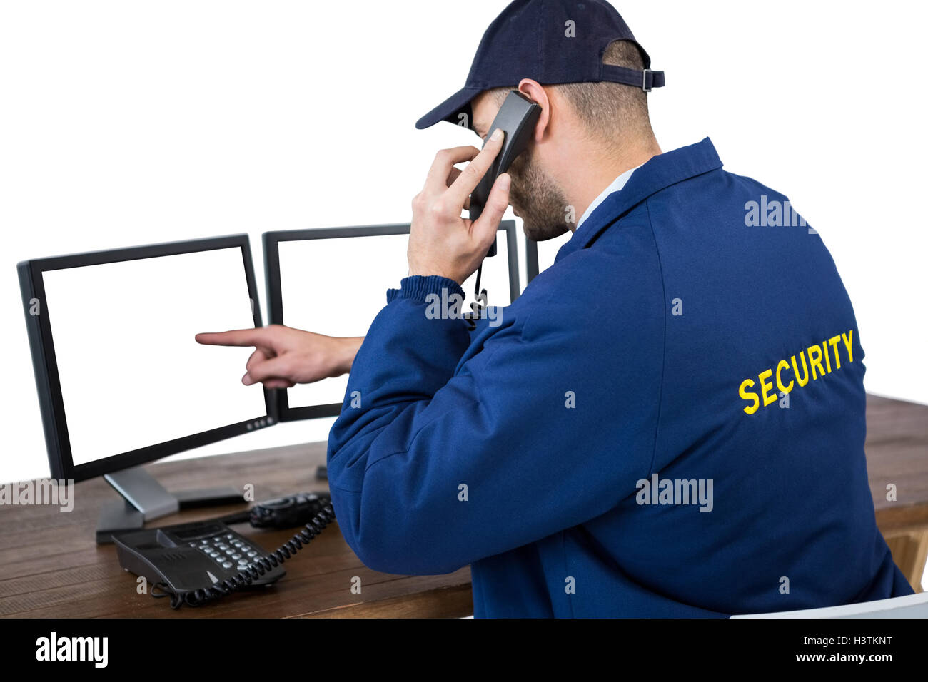 Security officer talking on phone while pointing at computer monitors ...