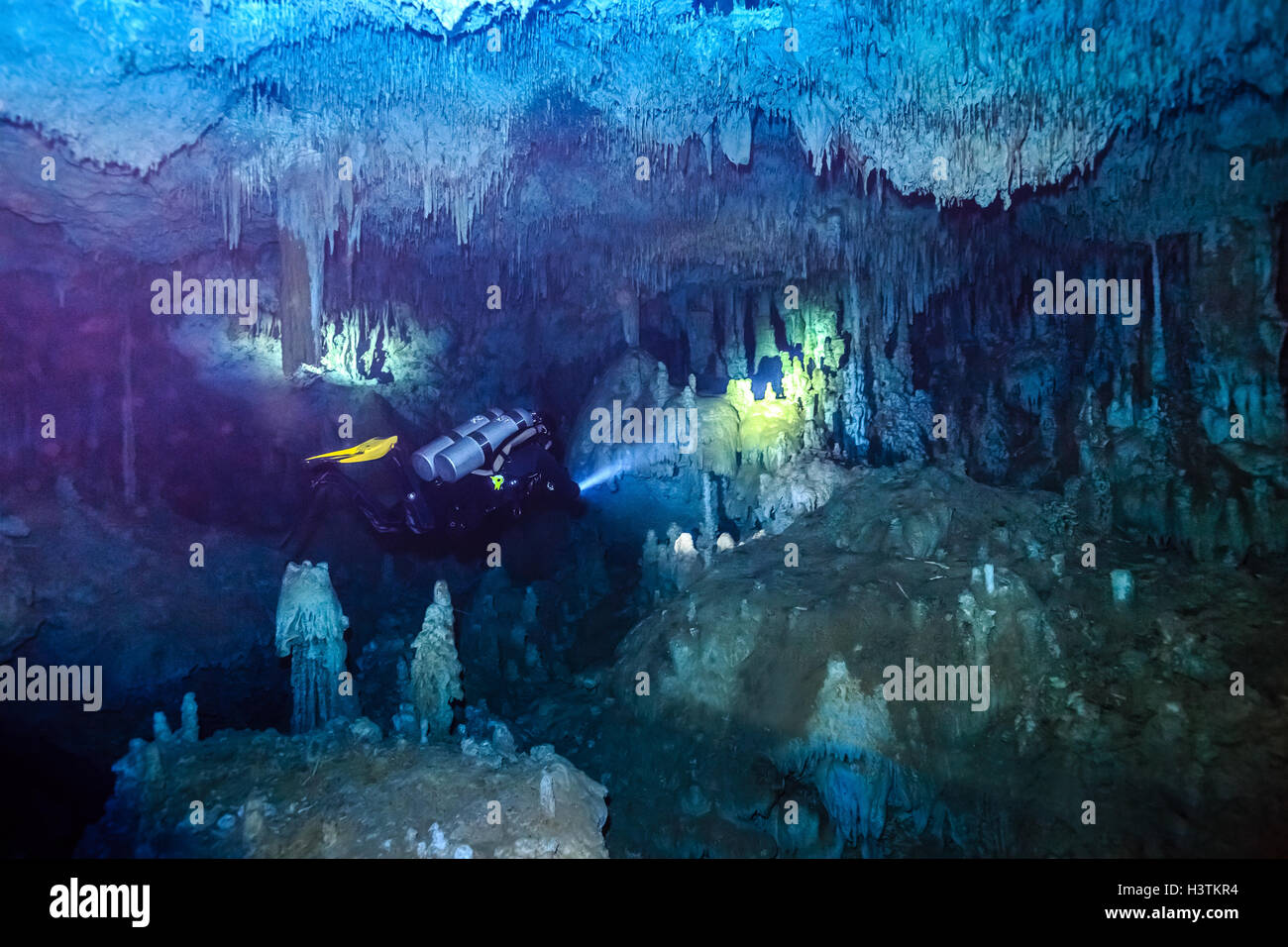 Diver in a cenote cave in Tulum, Mexico, surrounded by turquoise water ...
