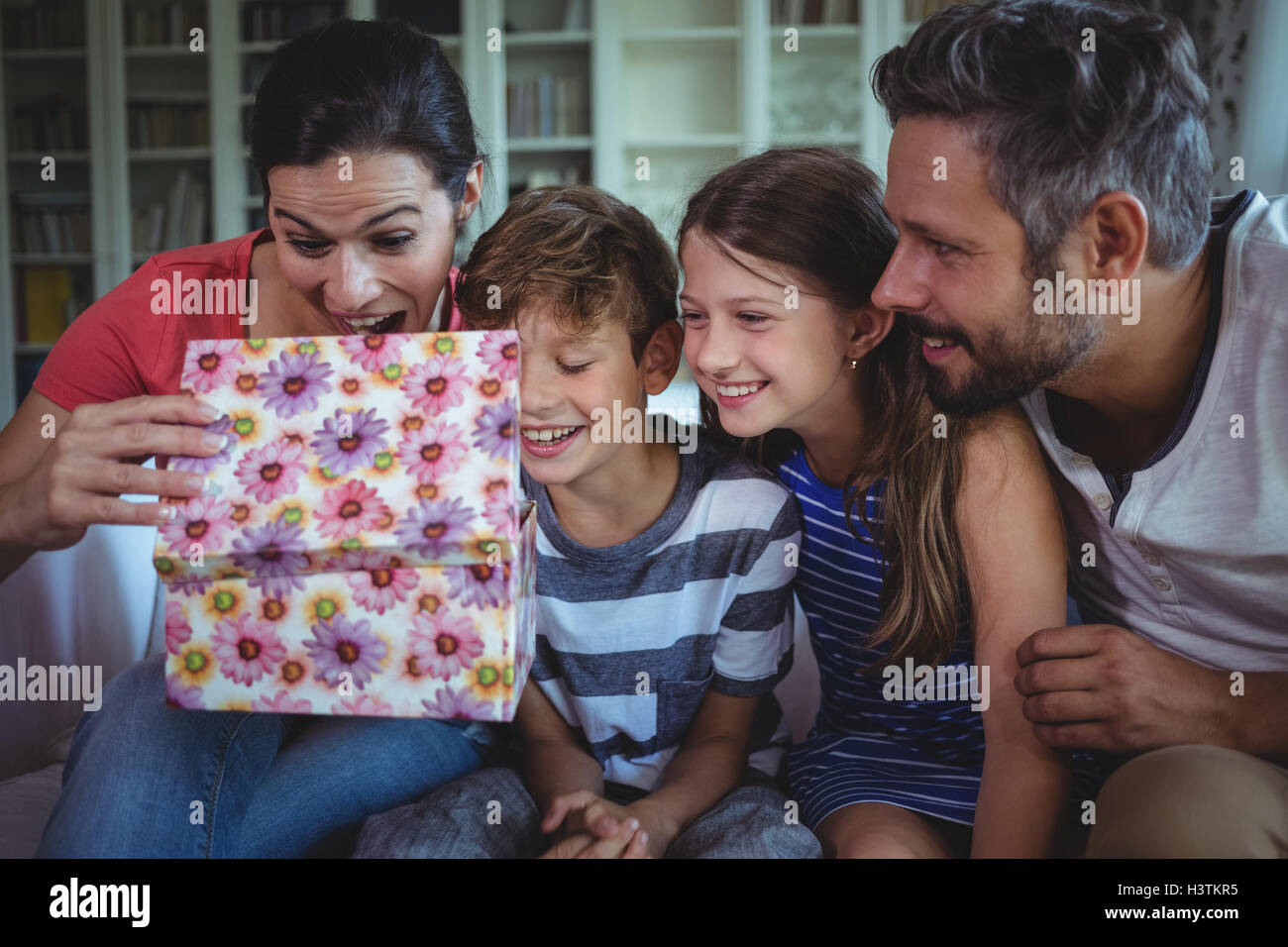 Family opening the surprise gift in living room Stock Photo - Alamy