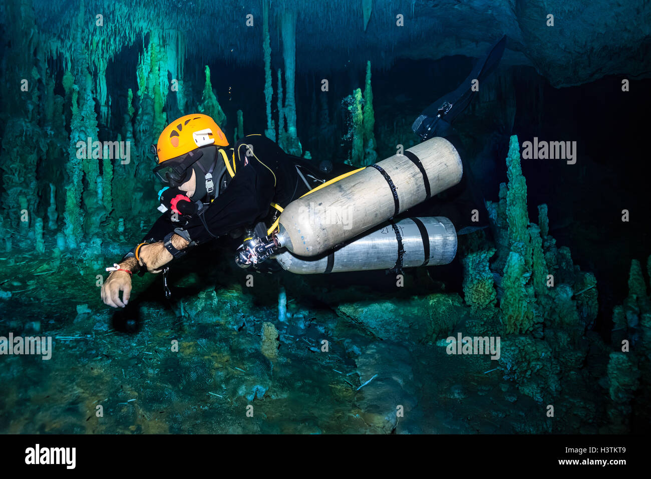 Diver in a cenote cave in Tulum, Mexico, surrounded by turquoise water ...