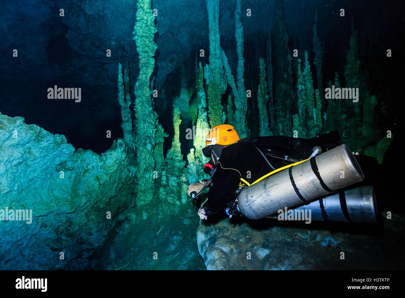 Diver in a cenote cave in Tulum, Mexico, surrounded by turquoise water ...