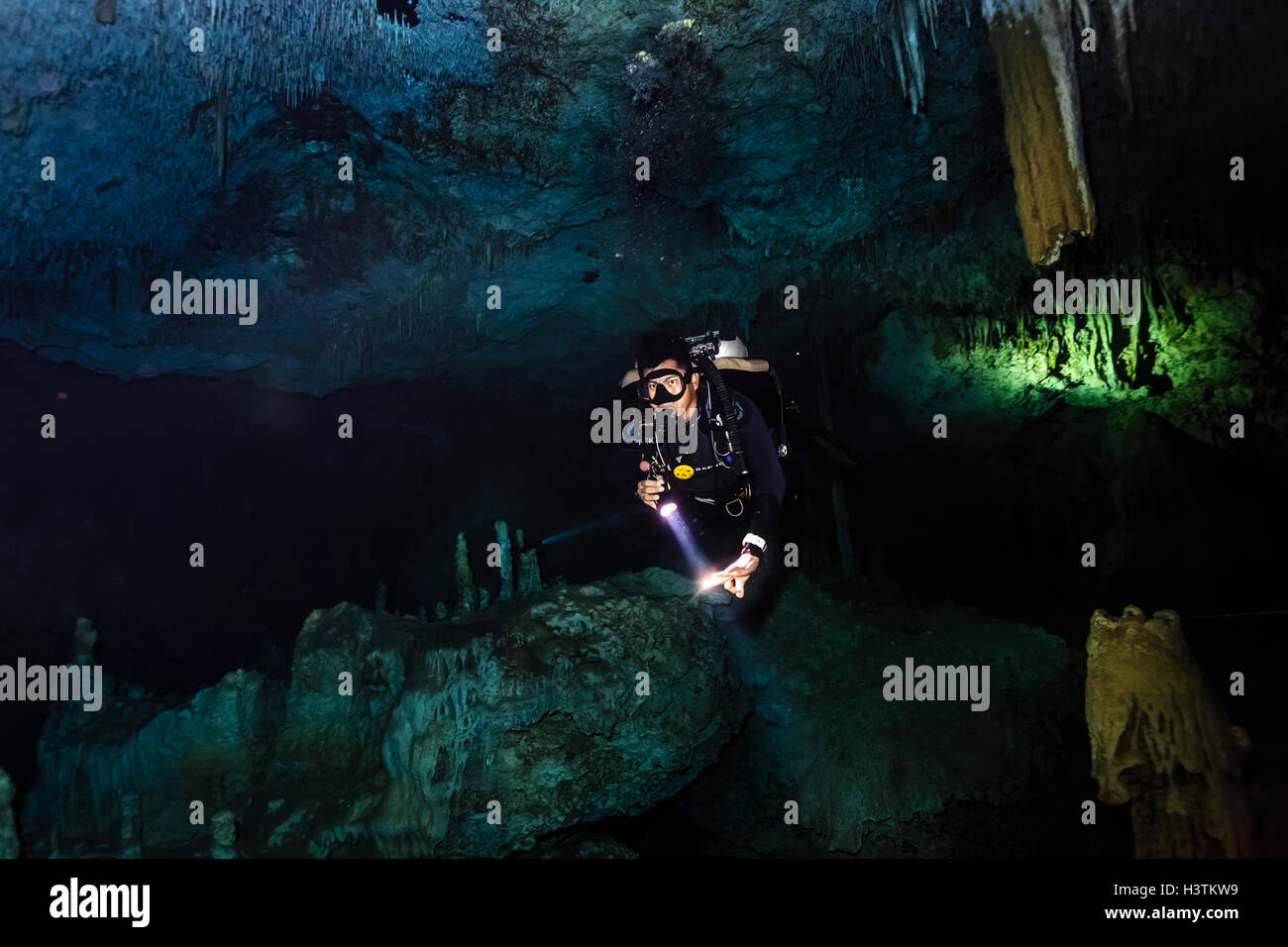 Diver in a cenote cave in Tulum, Mexico, surrounded by turquoise water ...