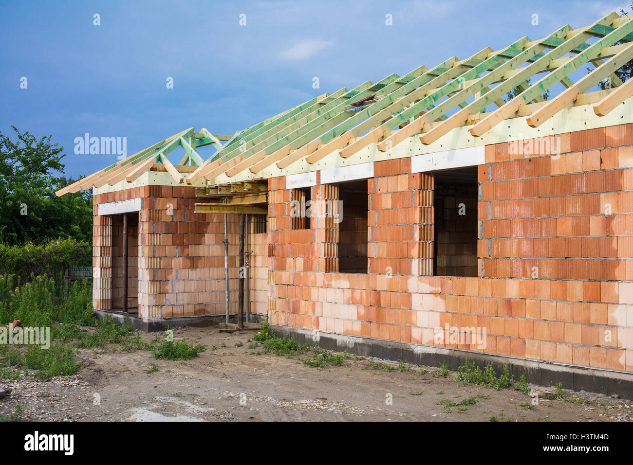 Unfinished brick house with wooden roof structure Stock Photo - Alamy