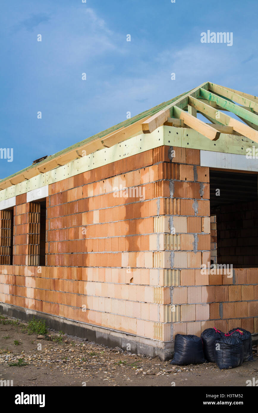 Unfinished brick house with wooden roof structure Stock Photo - Alamy
