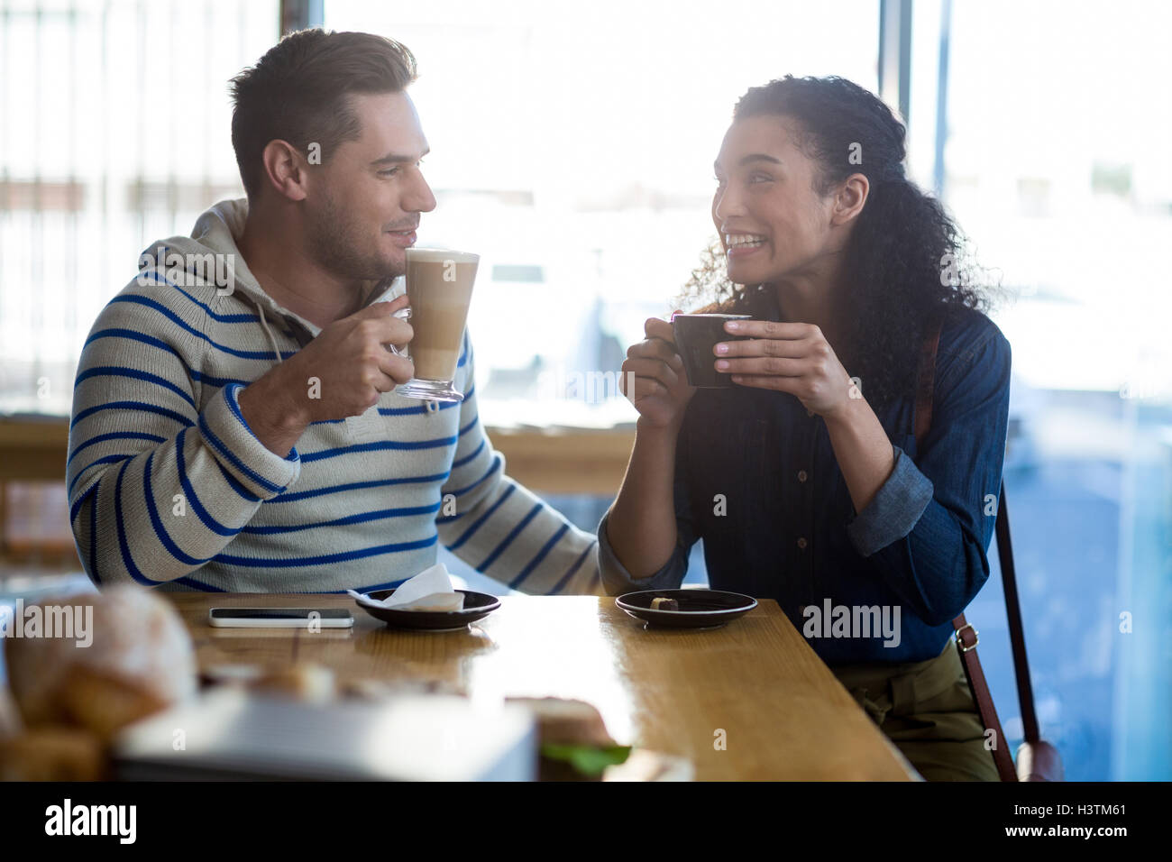 Smiling young couple having coffee in cafe Stock Photo - Alamy