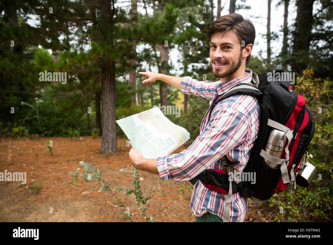 Male hiker holding a map and showing direction Stock Photo - Alamy