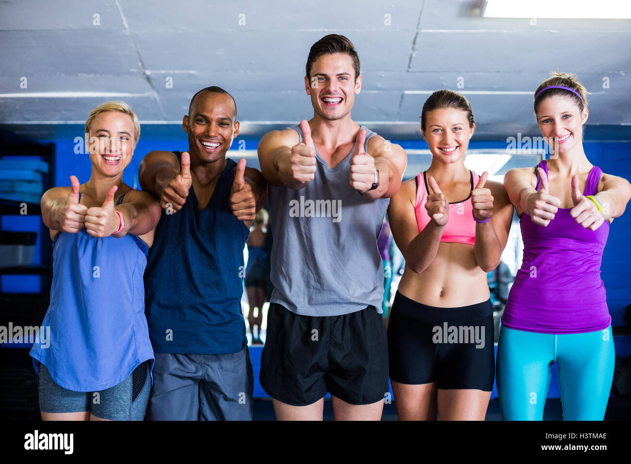 Portrait of smiling friends showing thumbs up in gym Stock Photo - Alamy