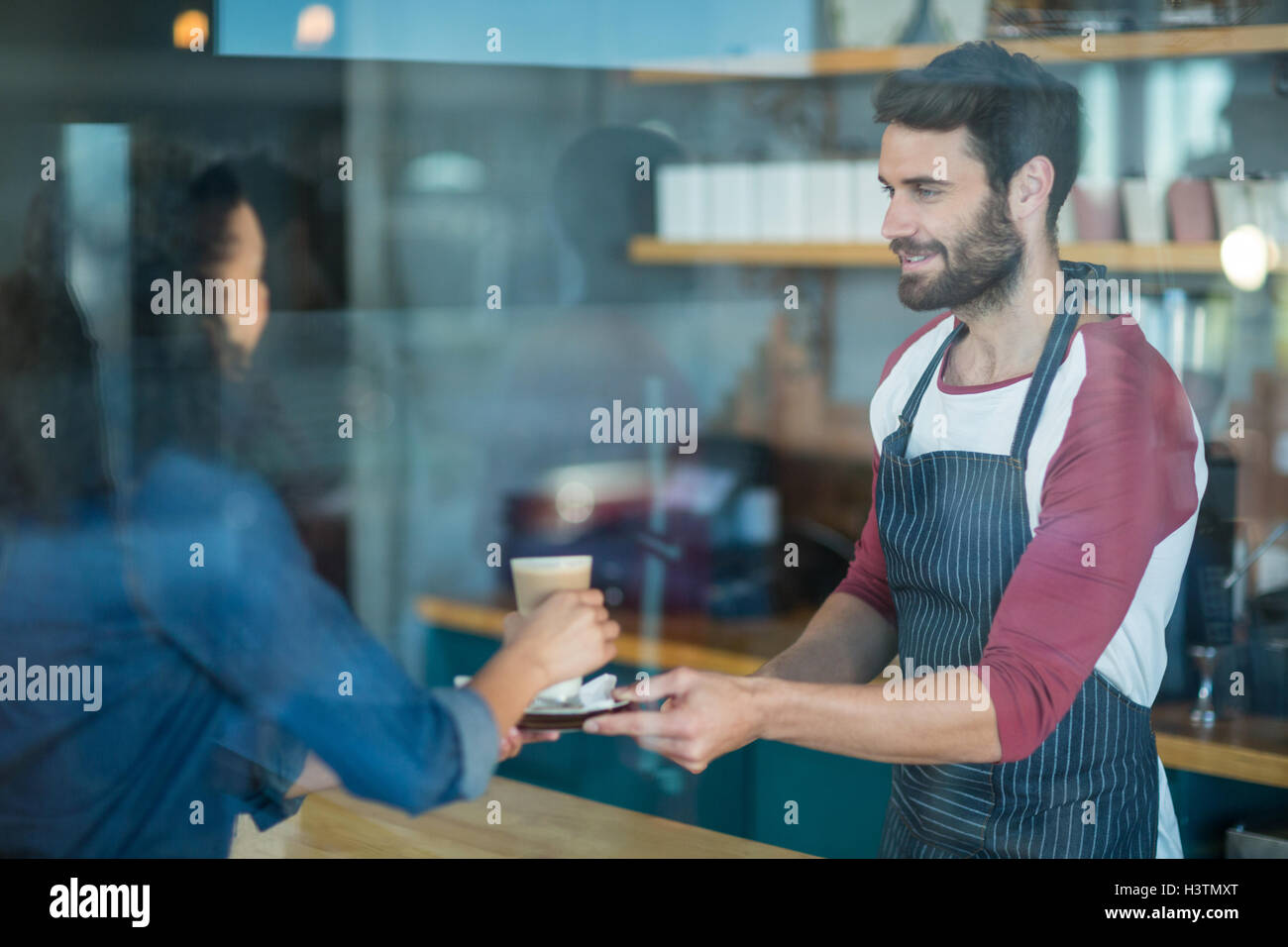 Waiter serving a cup of cold coffee to customer at counter Stock Photo ...