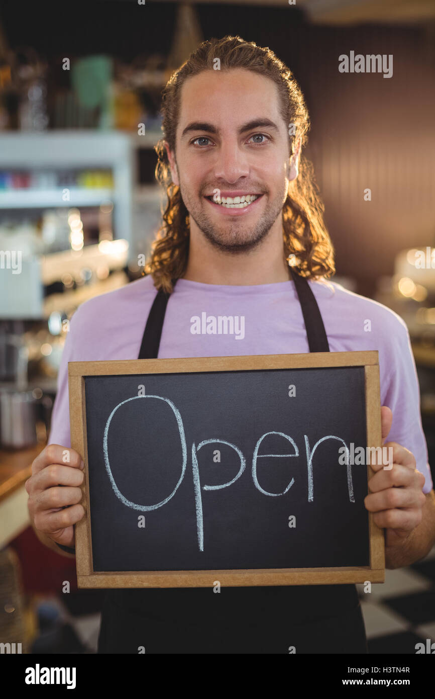 Portrait of smiling waiter holding chalkboard with open sign Stock ...