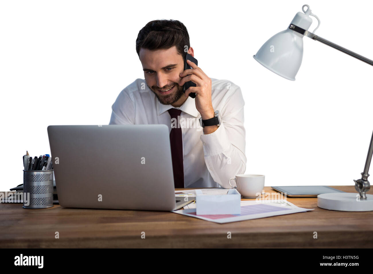 Businessman talking on mobile phone while working on laptop Stock Photo ...
