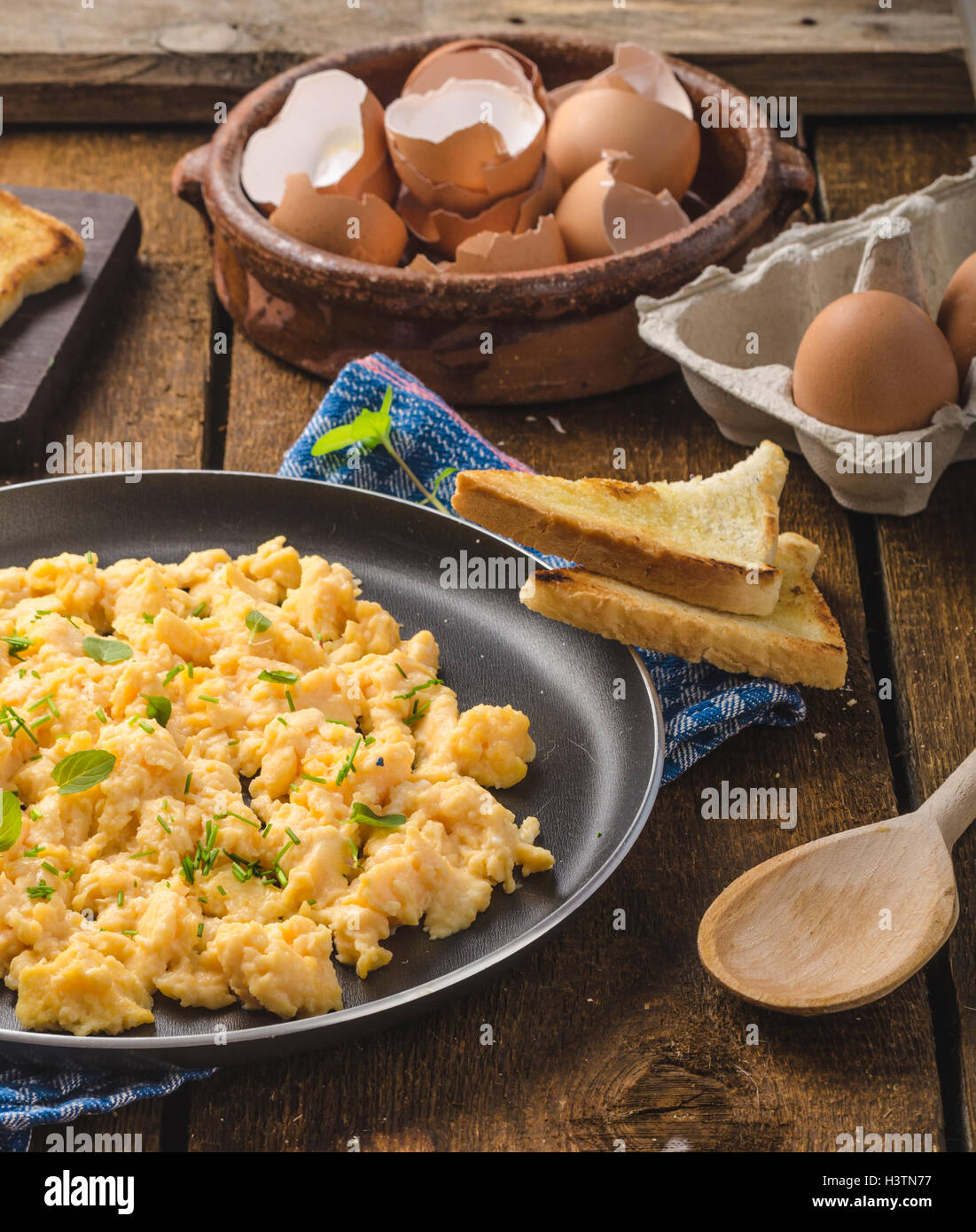 Scrambled eggs rustic style, with toast and herbs Stock Photo - Alamy