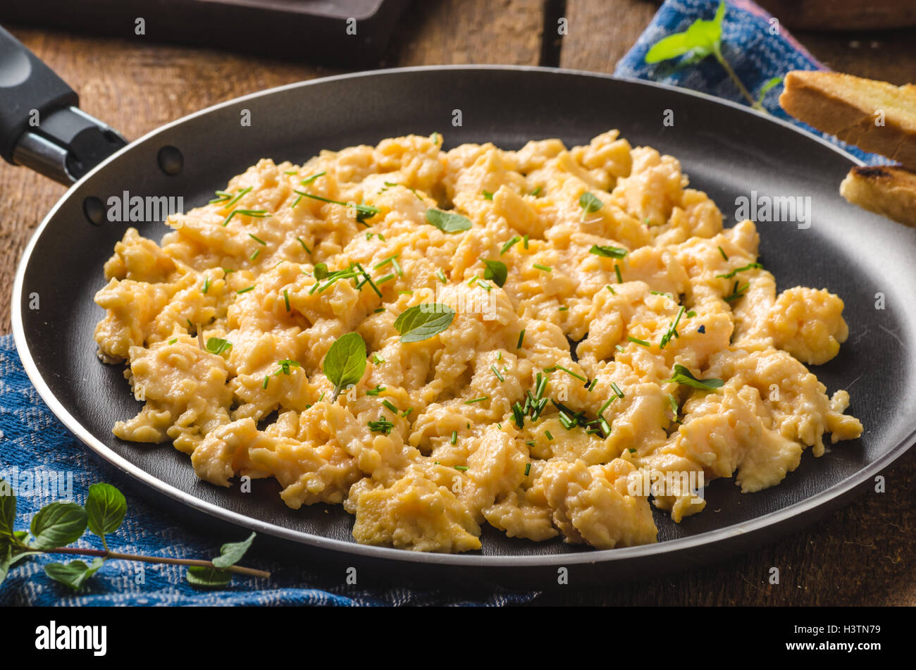 Scrambled eggs rustic style, with toast and herbs Stock Photo - Alamy