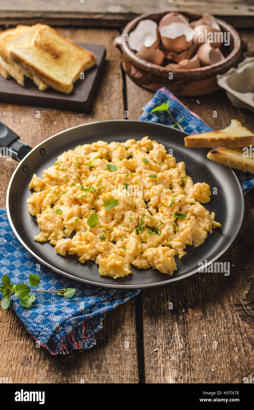 Scrambled eggs rustic style, with toast and herbs Stock Photo - Alamy
