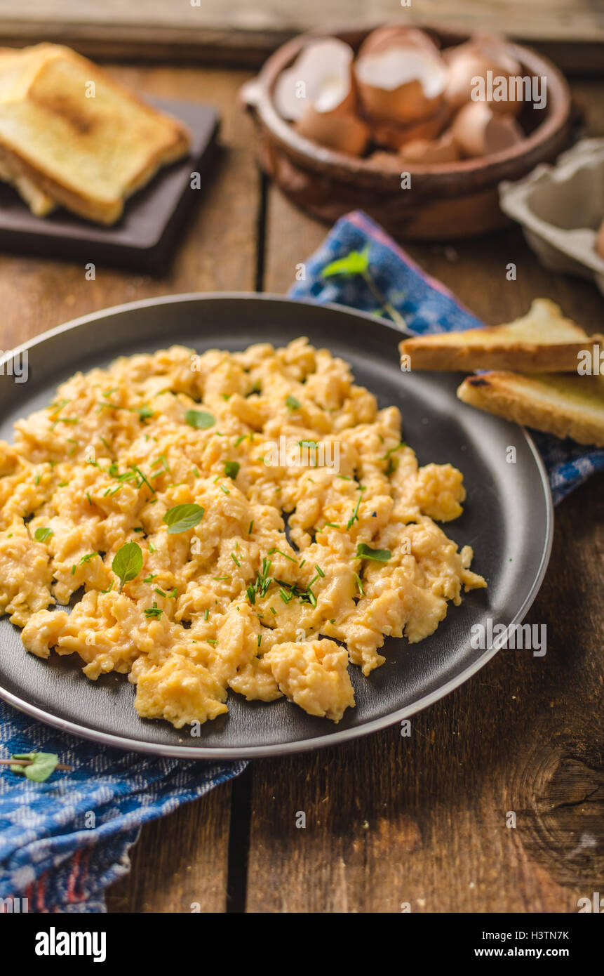 Scrambled eggs rustic style, with toast and herbs Stock Photo - Alamy