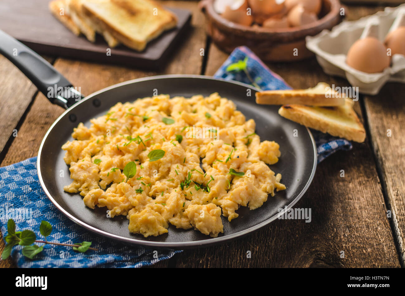 Scrambled eggs rustic style, with toast and herbs Stock Photo - Alamy