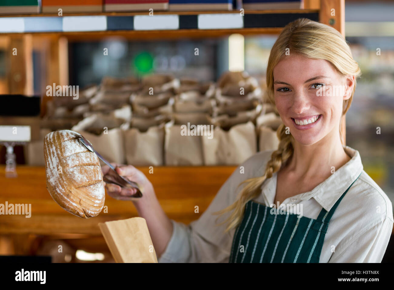 Female staff packing a bread in paper bag Stock Photo - Alamy