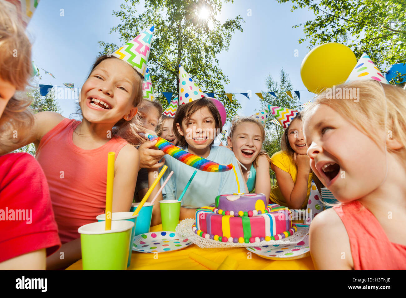 Group of funny kids having fun around party cake Stock Photo - Alamy