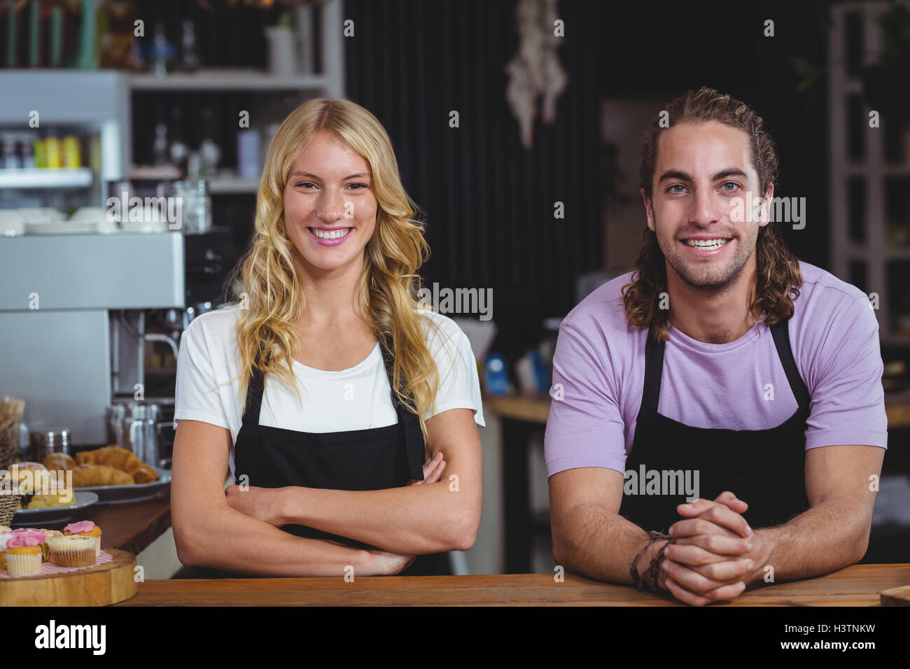 Portrait of smiling waiter and waitress standing at counter Stock Photo ...