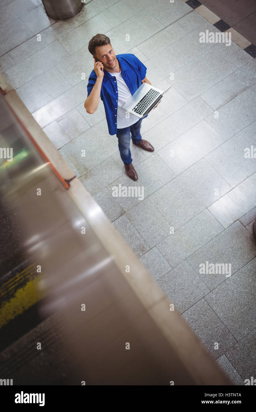 Handsome man talking on mobile phone while using laptop Stock Photo - Alamy