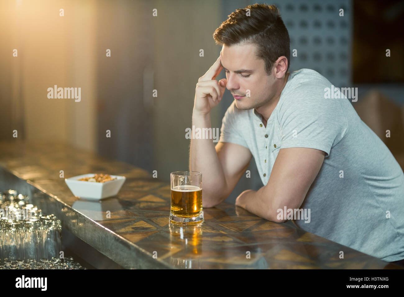Thoughtful man with glass of whisky sitting at bar counter Stock Photo ...