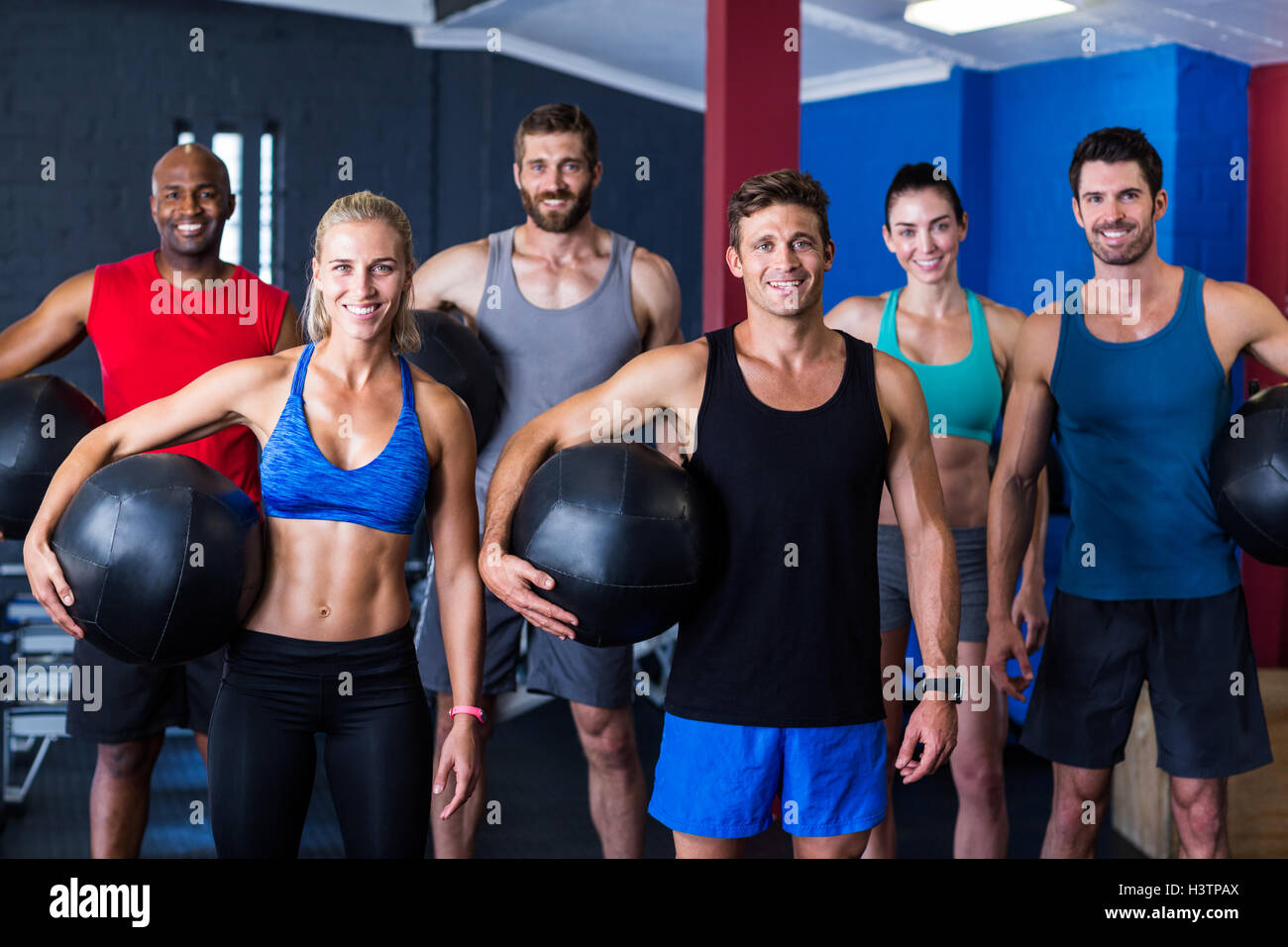 Portrait of smiling friends holding exercise ball in gym Stock Photo ...