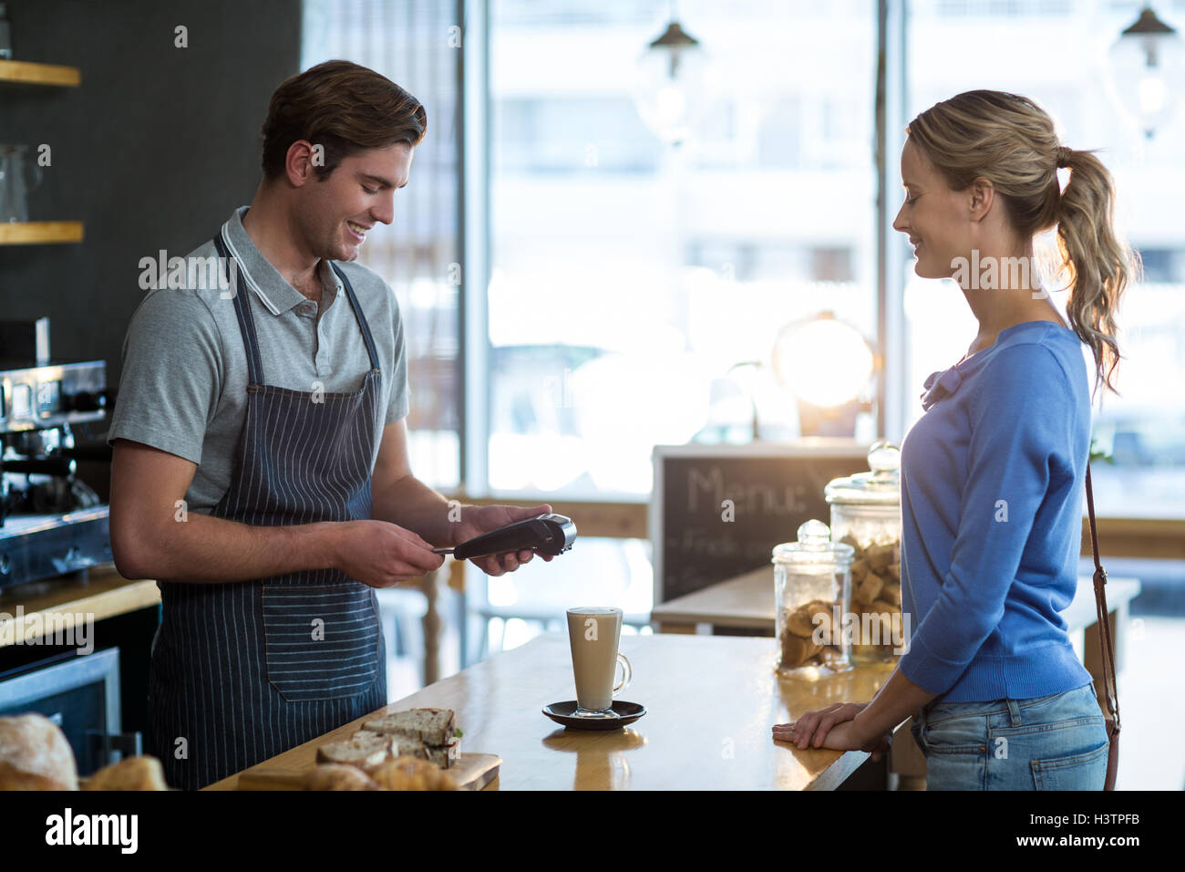 Customer making payment through payment terminal at counter Stock Photo ...
