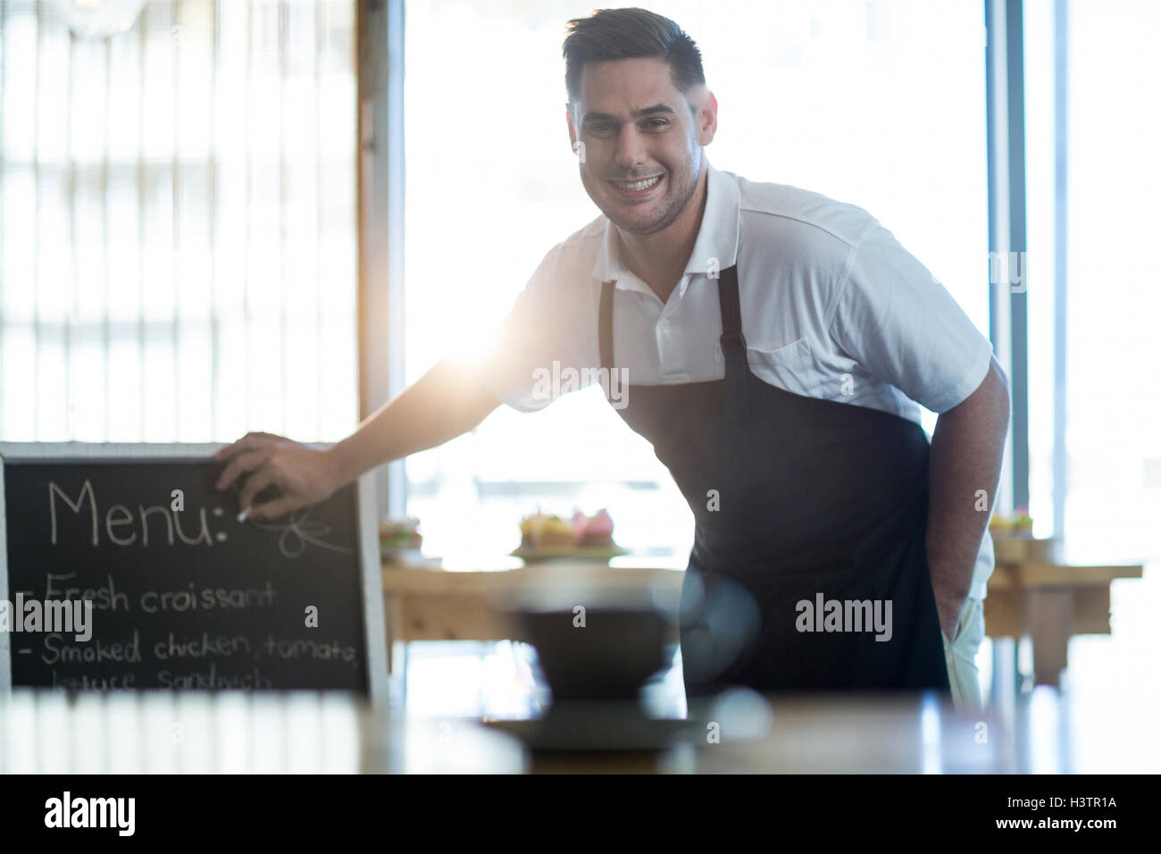 Smiling waiter writing on menu board in cafe Stock Photo - Alamy